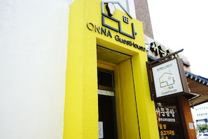 Exterior de um edifício amarelo com uma placa que diz 'ONNA GuestHouse'.
