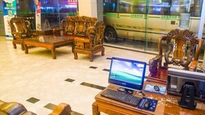 Um hall com mobiliário de madeira tradicional, um computador de mesa e um ônibus ao fundo.