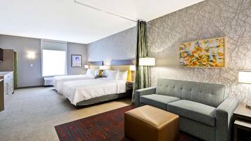 Quarto de hotel com cama, sofá, escrivaninha e janela.