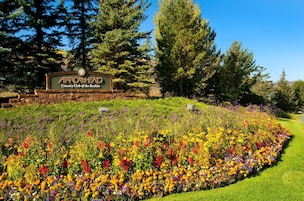 Placa do Arrowhead Country Club of the Rockies, rodeada por um vibrante jardim florido.