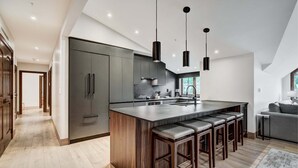 Uma cozinha moderna com uma ilha central, banquetas e iluminação pendente.