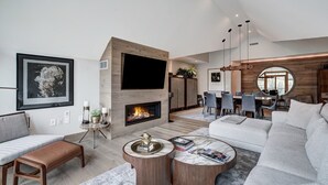 Uma sala de estar moderna com lareira, um sofá, uma mesa de centro e um espaço de jantar com cadeiras e mesa.