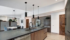 Uma cozinha moderna com uma ilha grande, eletrodomésticos embutidos e iluminação pendente.