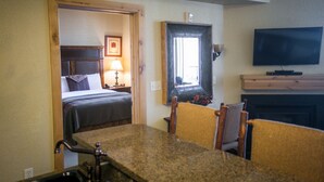 Quarto de hotel com cama, escrivaninha, cadeira, televisão e lareira.