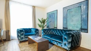 Sala de estar com sofá azul, mesa de centro e duas pinturas abstratas na parede.