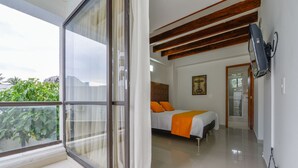 Quarto com cama, televisão e janela com cortinas.
