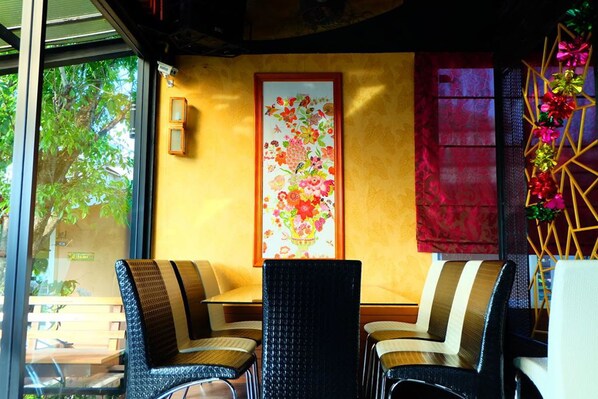 Uma sala de jantar com cadeiras de vime, uma mesa e uma parede decorativa com uma pintura floral.