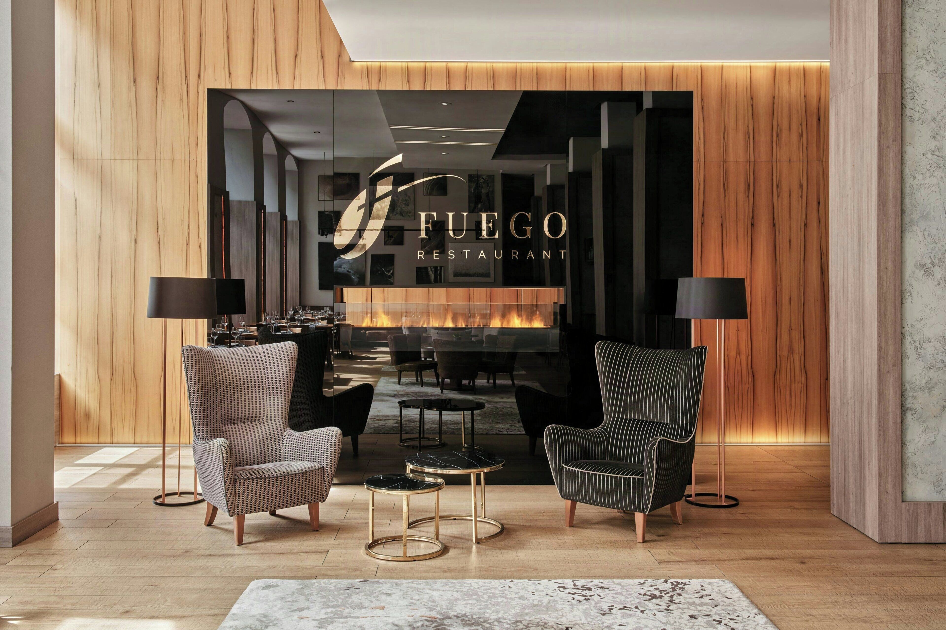 Um interior moderno com lareira, dois poltronas e uma pequena mesa.