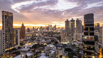 Paisagem urbana ao pôr do sol, com edifícios altos, incluindo um hotel em destaque chamado 'Hyatt Place'.