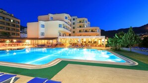 Um hotel com piscina, área de estar externa e fachada bem iluminada.
