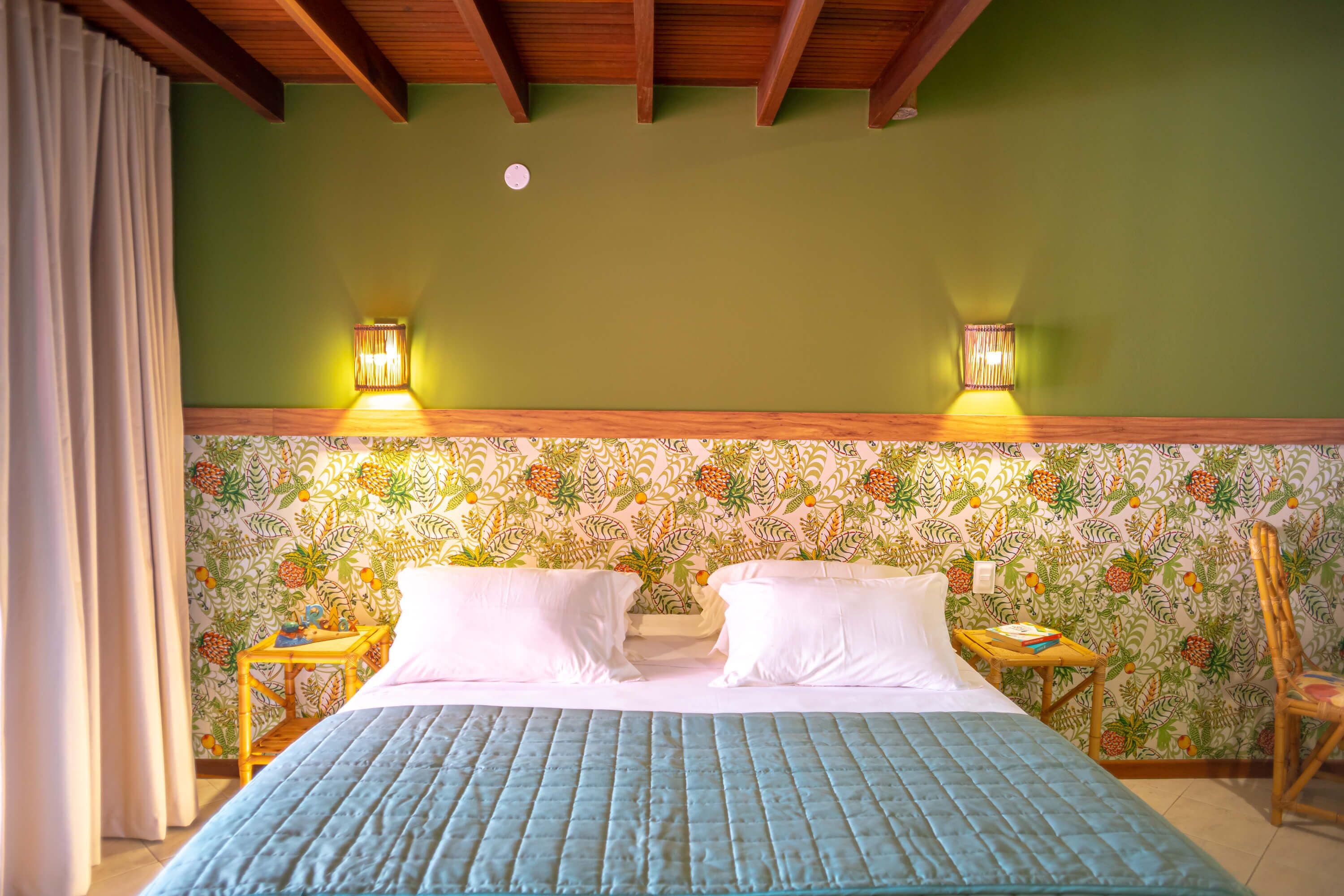 Quarto com cama, duas mesas de cabeceira, uma cadeira e papel de parede floral.