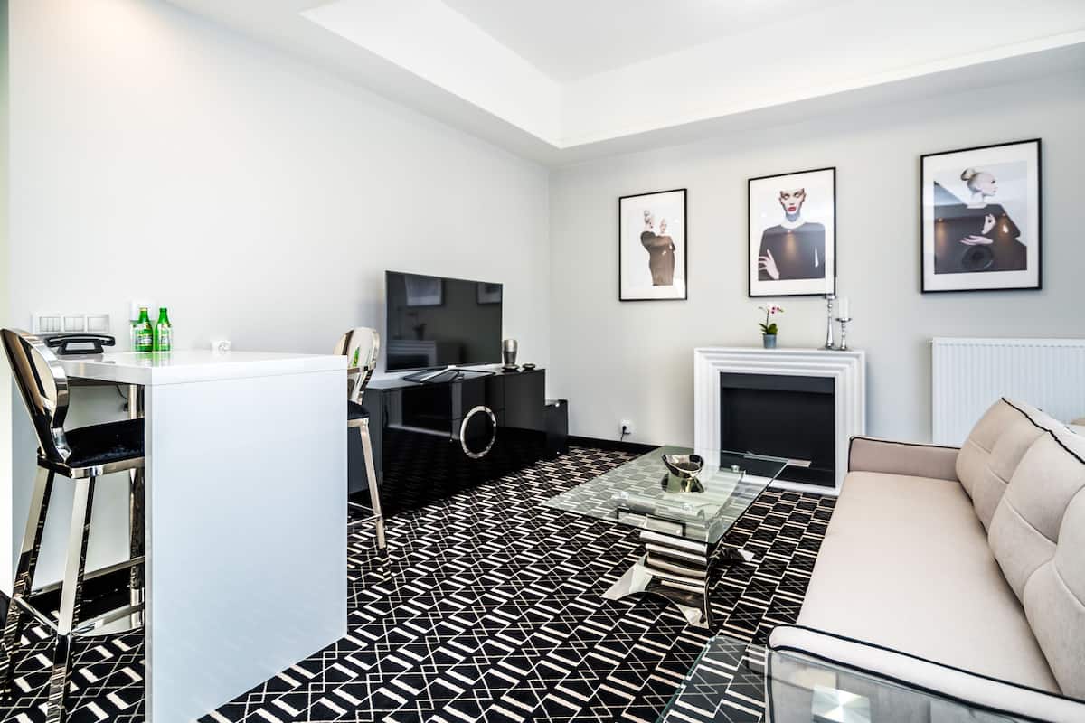 Uma sala de estar moderna com piso estampado em preto e branco, um sofá, uma mesa de centro, uma TV e obras de arte emolduradas na parede.