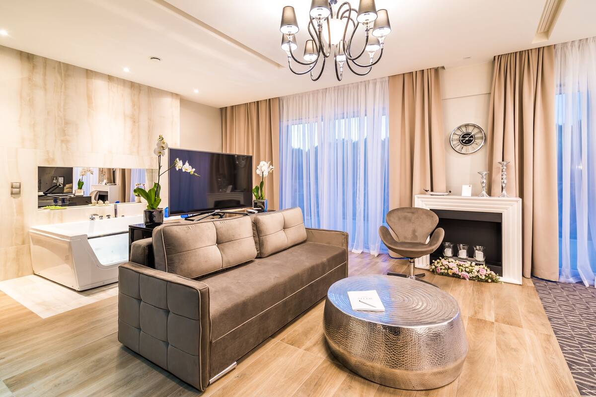 Uma sala de estar moderna com um sofá, uma mesa de centro redonda, uma televisão e uma lareira.