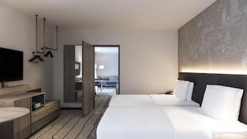 Quarto de hotel com uma cama grande, uma televisão, uma escrivaninha e um mapa na parede.