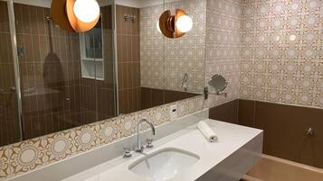 Uma casa de banho moderna com um espelho grande, lavatório e banheira.
