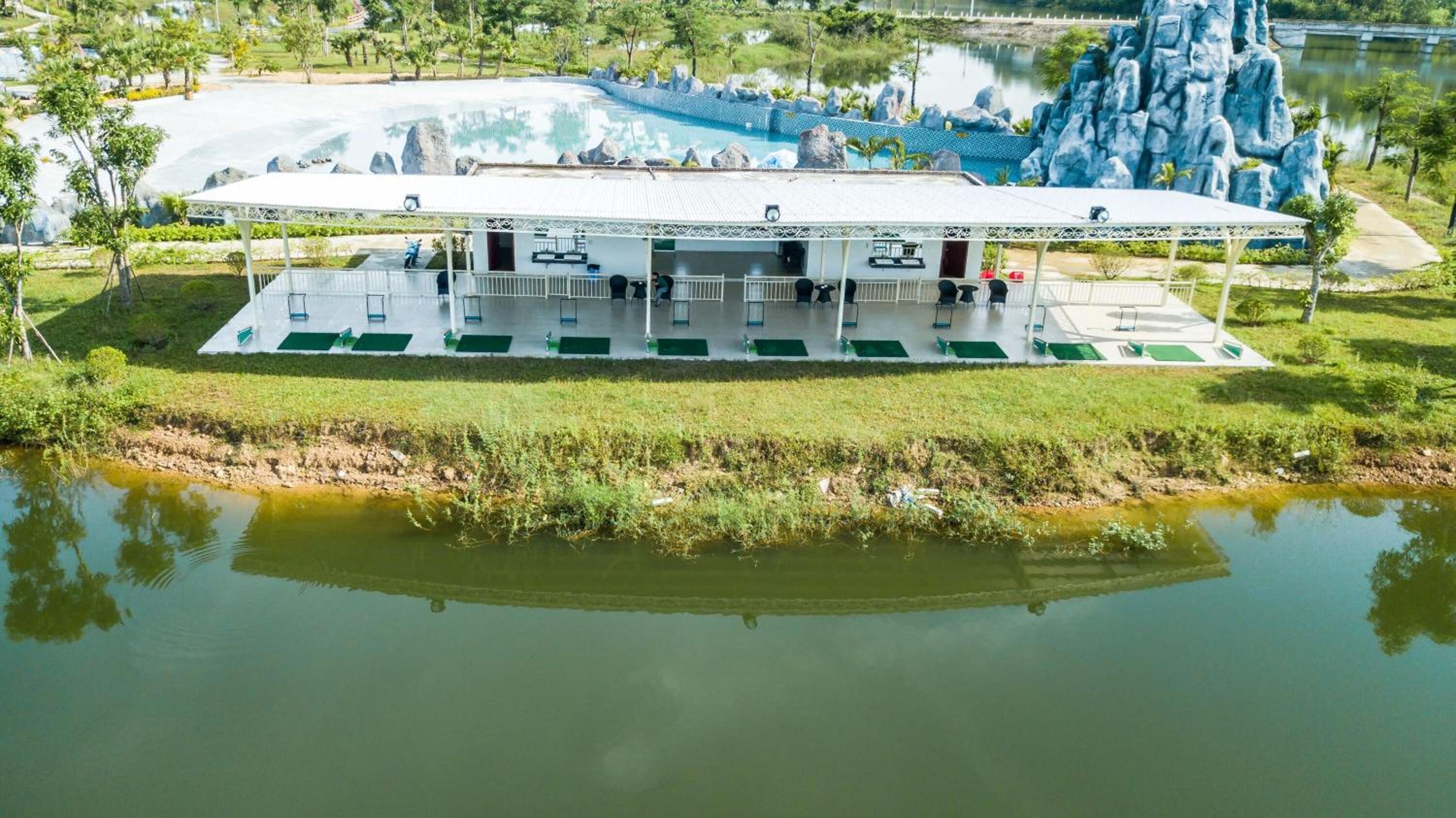 Uma área externa coberta com assentos e vista para um lago.
