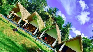 Um resort com cabanas de telhado de palha, piscina e vegetação exuberante.