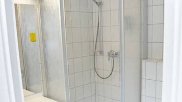 Casa de banho moderna com chuveiro em cabine de vidro, lavatório branco e sanita.