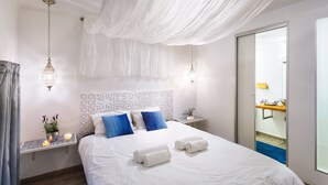 Quarto bem arrumado com uma cama grande, mesas de cabeceira e um lustre.