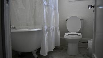 Um banheiro com banheira, vaso sanitário e cortina de chuveiro.