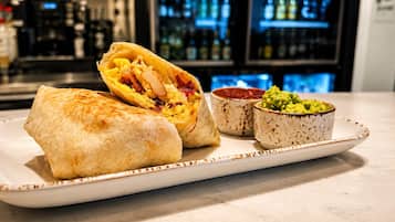 Um prato com um burrito, guacamole e salsa.