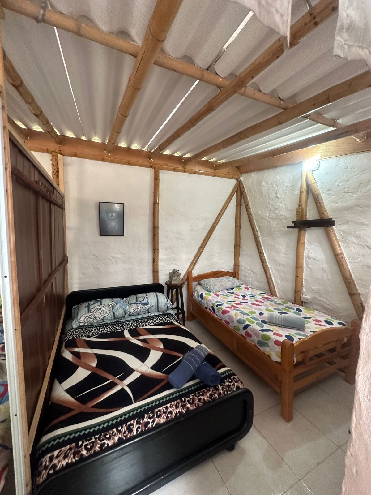Quarto com uma cama, uma cama menor e estrutura de teto de madeira.
