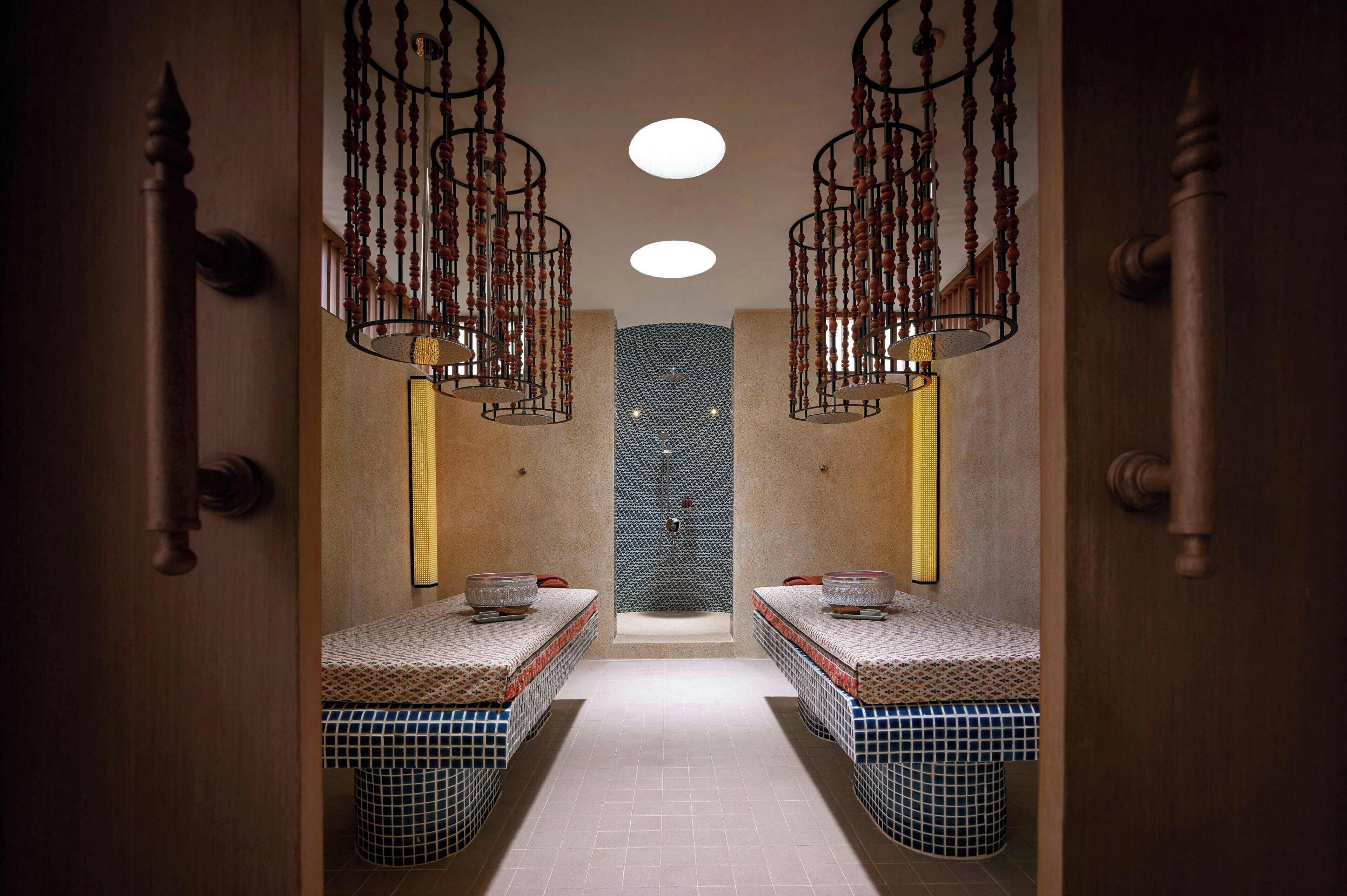 Um espaço de spa com duas bancos, parede estampada e teto com luminárias pendentes.