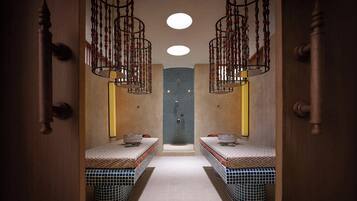 Um espaço de spa com duas bancos, parede estampada e teto com luminárias pendentes.