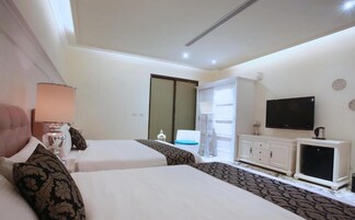 Quarto de hotel com duas camas, televisão, guarda-roupa e janela com vista.