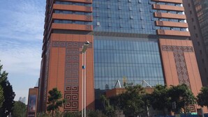 Um edifício alto e moderno, com fachada de vidro e um padrão característico na parte inferior.