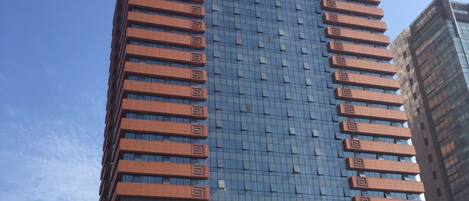 Um edifício alto e moderno, com fachada de vidro e um padrão característico na parte inferior.