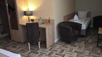 Quarto de hotel com cama, escrivaninha, cadeira, mesinha de centro e guarda-roupa.