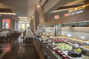 Uma área de buffet com diversas opções de comida e um espaço de refeições com mesas e cadeiras.