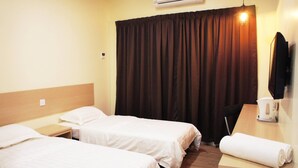Quarto de hotel com duas camas de solteiro, cabeceira de madeira, escrivaninha com chaleira e televisão na parede.