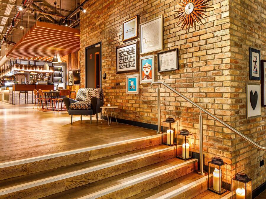 Um interior moderno com parede de tijolos, escadas de madeira e um espaço de bar.