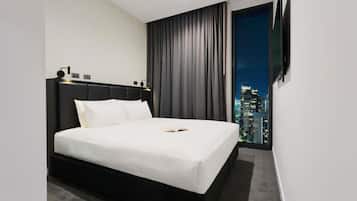 Quarto de hotel com cama, vista para a cidade, televisão de tela plana e janela com cortinas.
