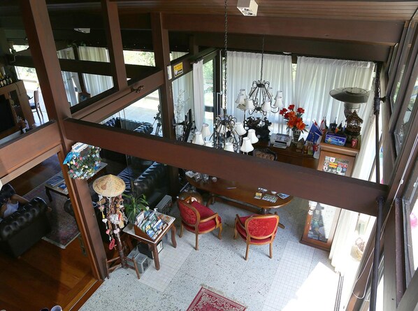 Uma sala de estar espaçosa com pé direito alto, grandes janelas e vista para o exterior.