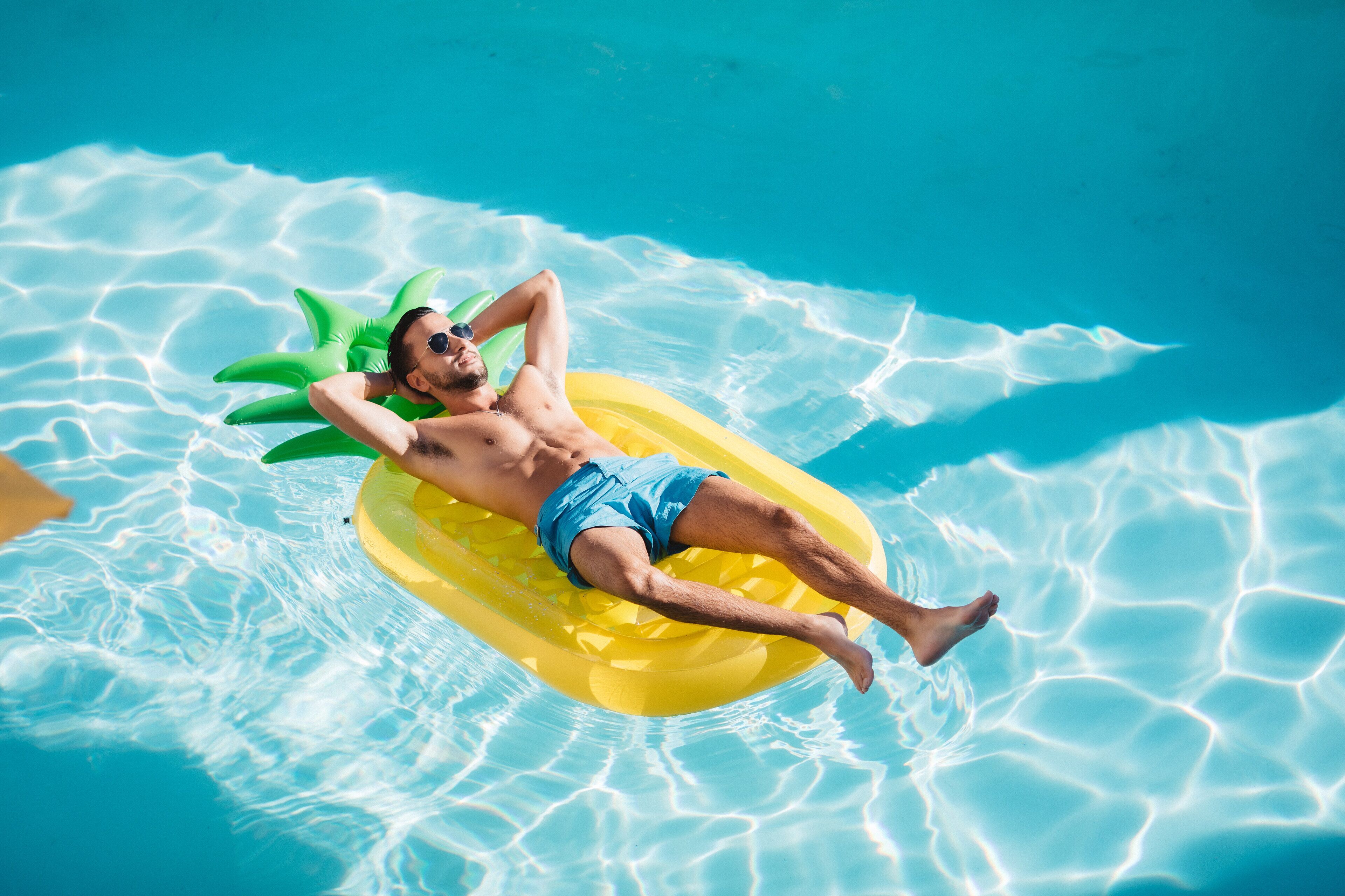 Uma pessoa deitada em um brinquedo flutuante amarelo em uma piscina.