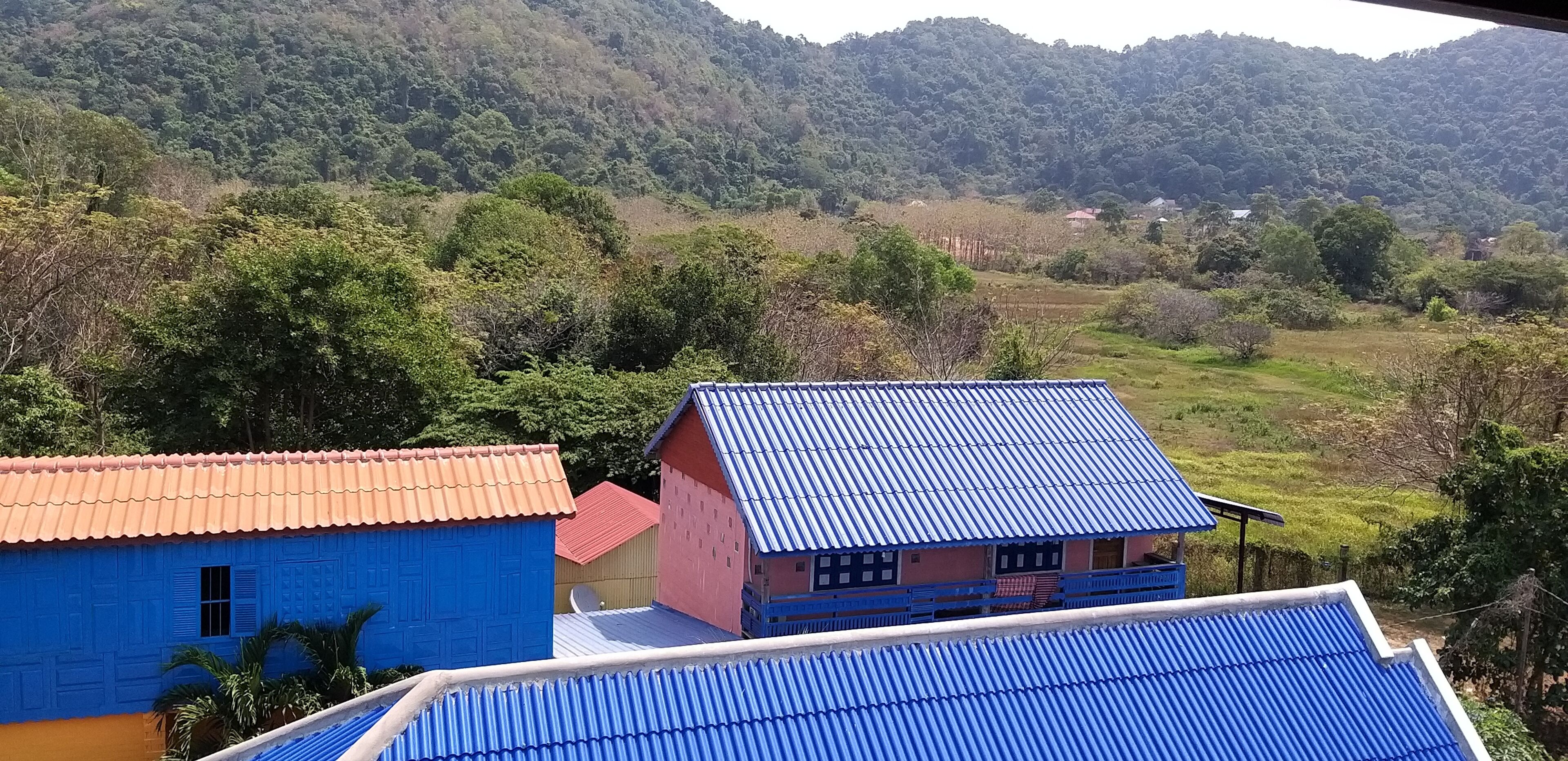 Uma aldeia rural com casas coloridas e uma paisagem verdejante.