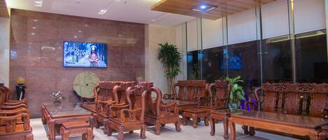 Um hall de entrada com mobiliário de madeira tradicional, uma grande tela de TV e um design de teto moderno.