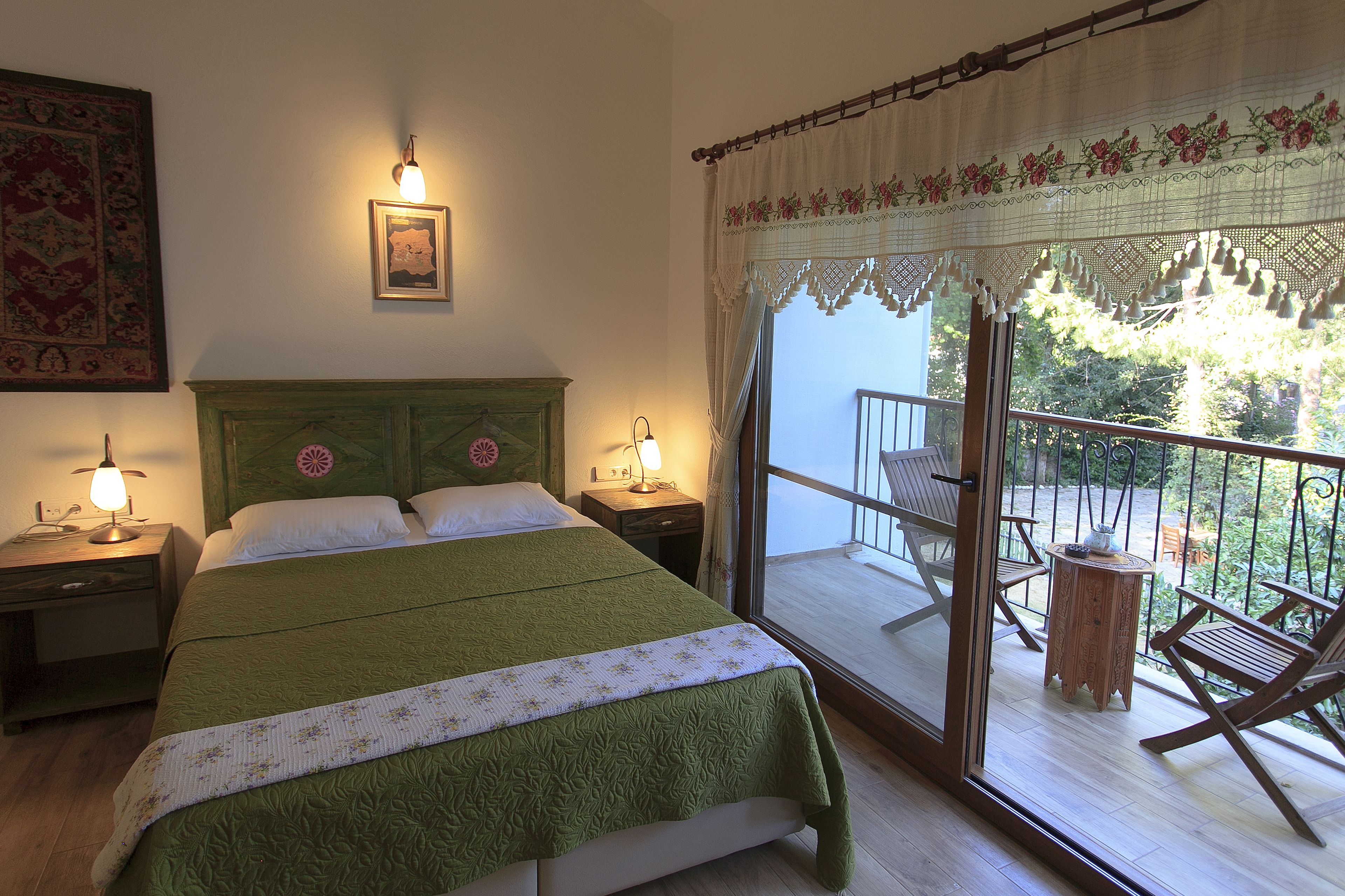 Quarto com uma cama grande, duas mesas de cabeceira com luminárias, uma janela com vista para a varanda e uma cabeceira decorativa.