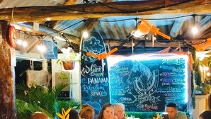 Um grupo de pessoas jantando em um restaurante com decoração rústica e um cardápio em lousa.