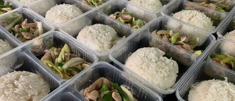 Vários recipientes de plástico cheios de arroz, diferentes vegetais e carnes.