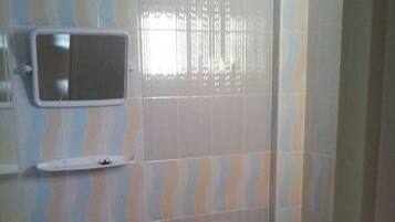 Uma casa de banho com lavatório, sanita e uma pequena prateleira sobre o lavatório.