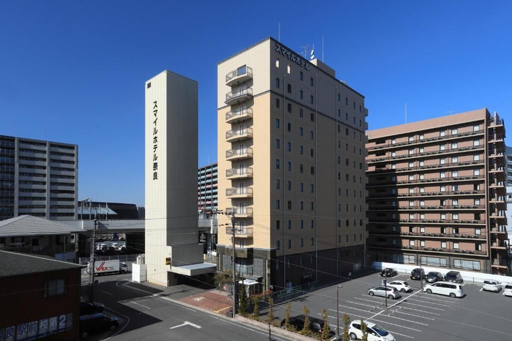 Hotel com vários andares, uma torre central e um estacionamento na frente.