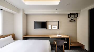 Quarto de hotel moderno com claraboia, uma cama, escrivaninha, cadeira, televisão e cabideiro.
