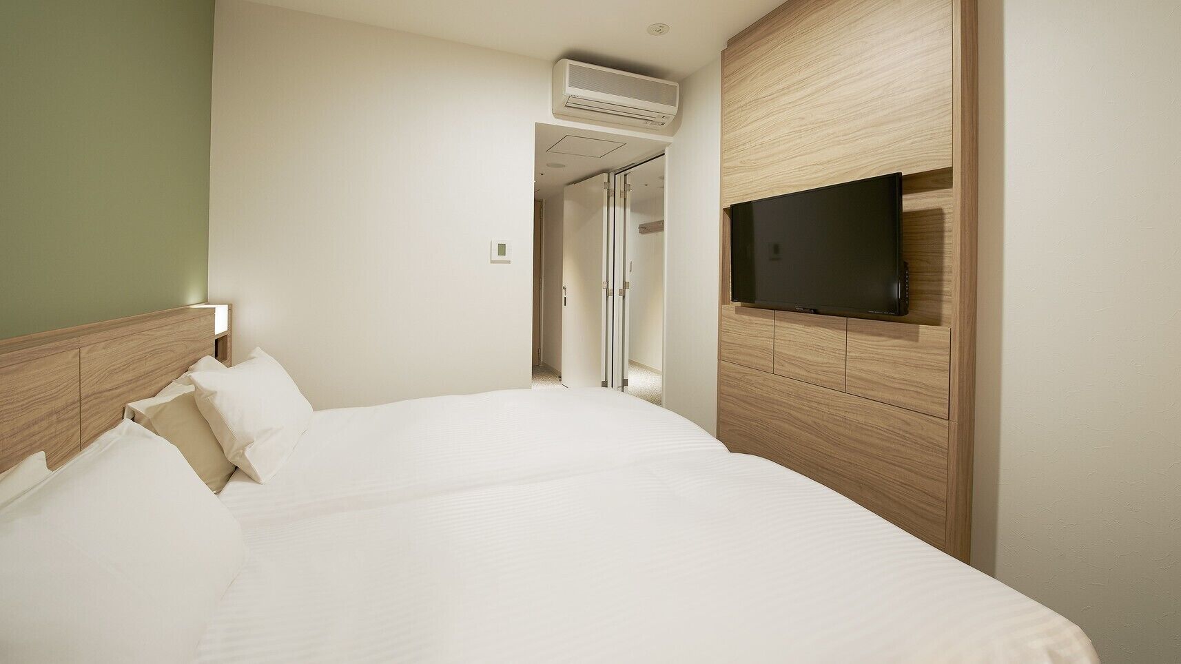 Quarto de hotel com cama, televisão e ar condicionado fixado na parede.