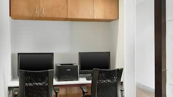 Um espaço de trabalho com dois monitores, uma impressora e duas cadeiras de escritório.
