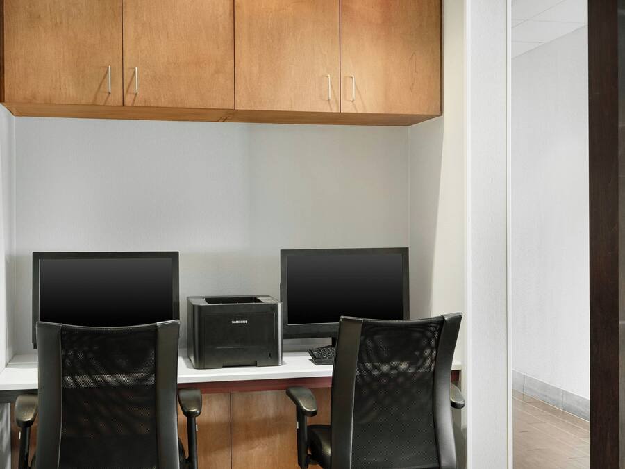 Um espaço de trabalho com dois monitores, uma impressora e duas cadeiras de escritório.
