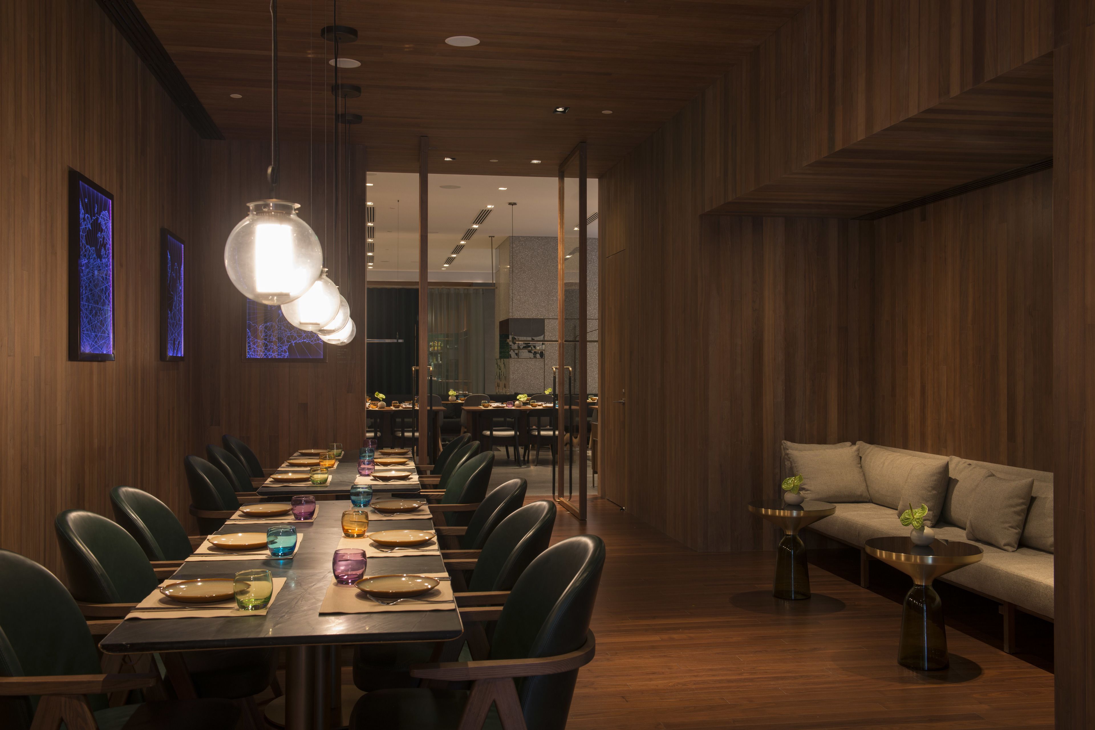 Uma sala de jantar moderna com uma mesa comprida, cadeiras e luminárias pendentes.
